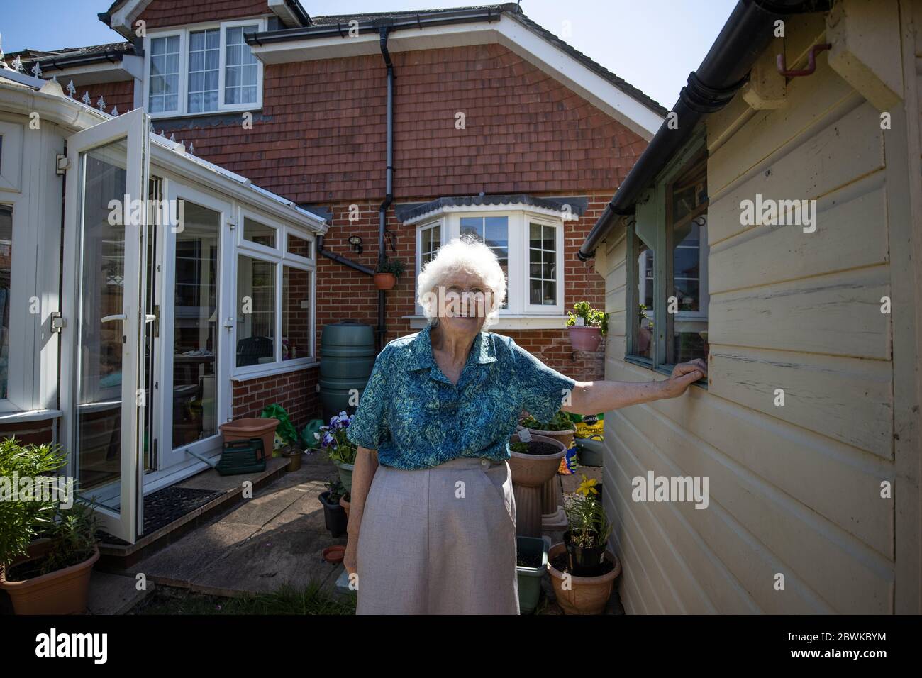 Elderly woman in her 80's, enjoying the sunny weather in her back ...