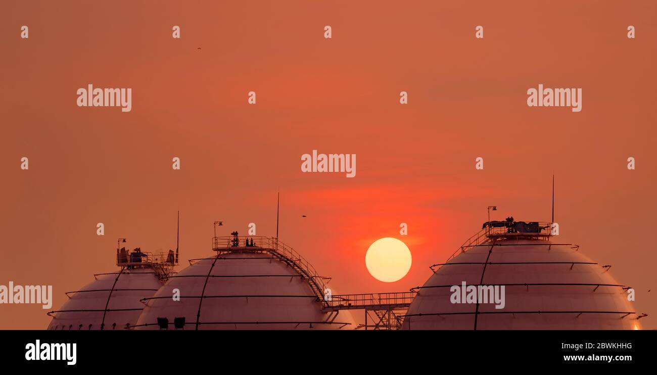 Industrial gas storage tank on orange sunset sky. LNG or liquefied ...