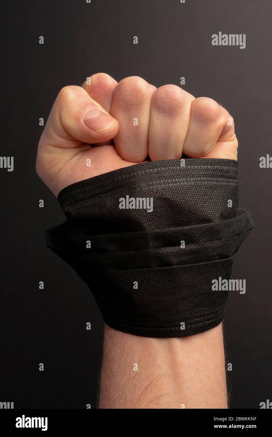 Fist with a black medical protective mask on a dark black background ...