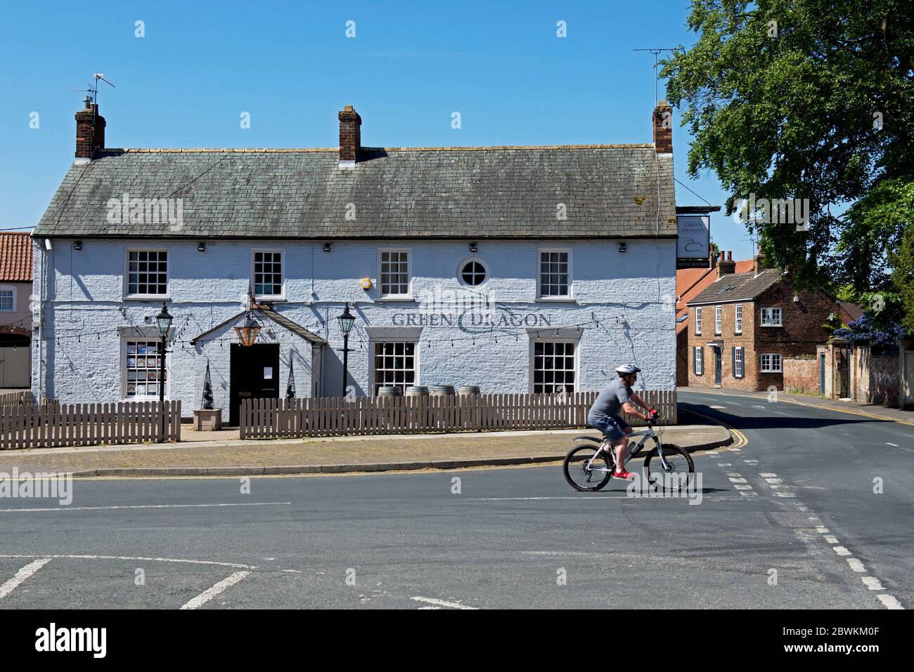Man cycling past the Green Dragon pub in the village of Welton, East ...