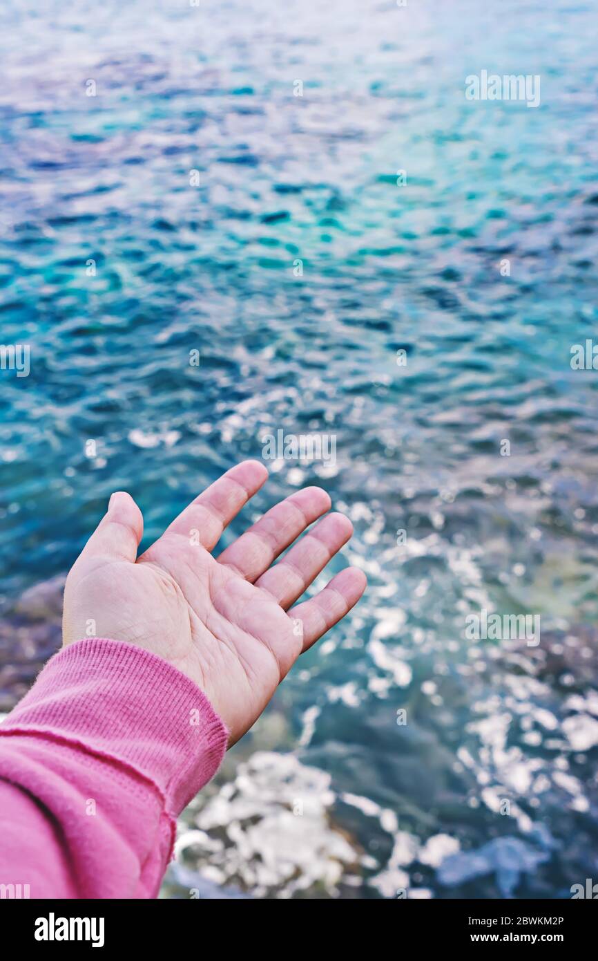 Female hand with an open palm reaches for surface of the water. Ocean ...