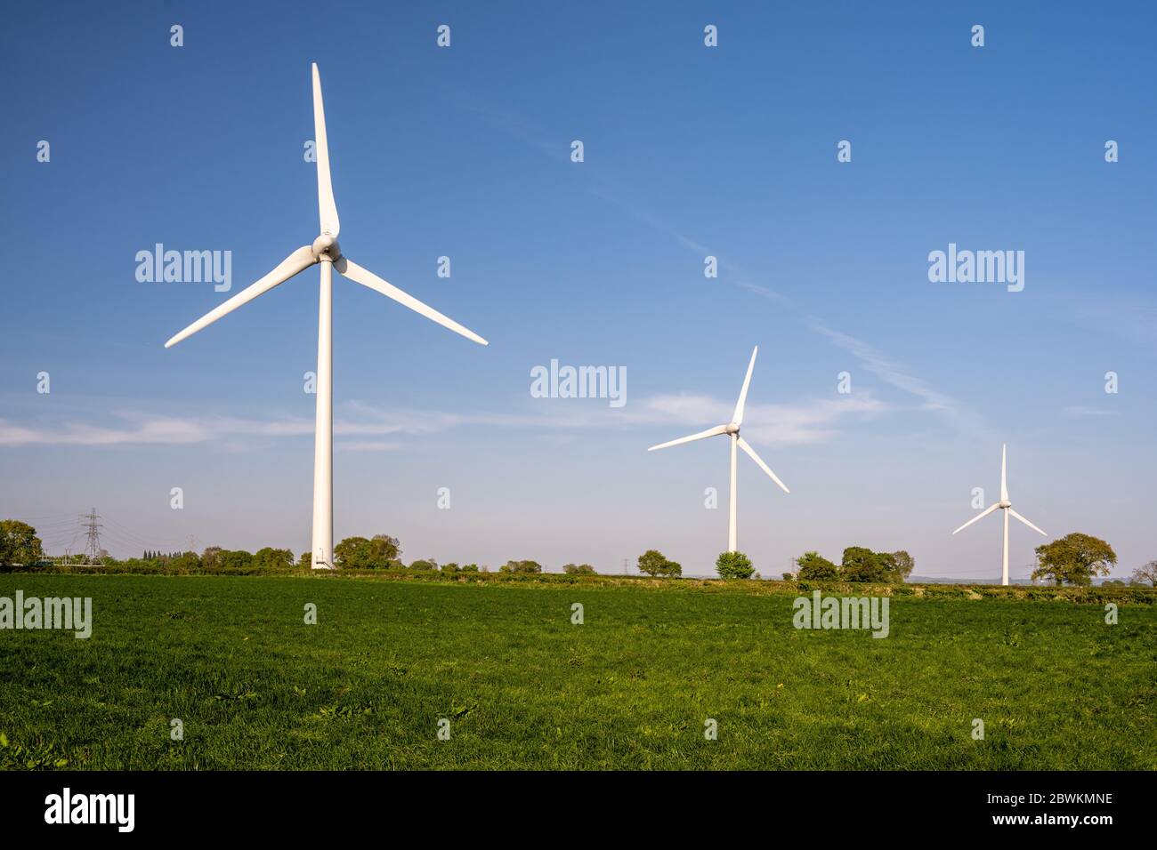Wind turbines stand in farmland fields beside National Grid high ...