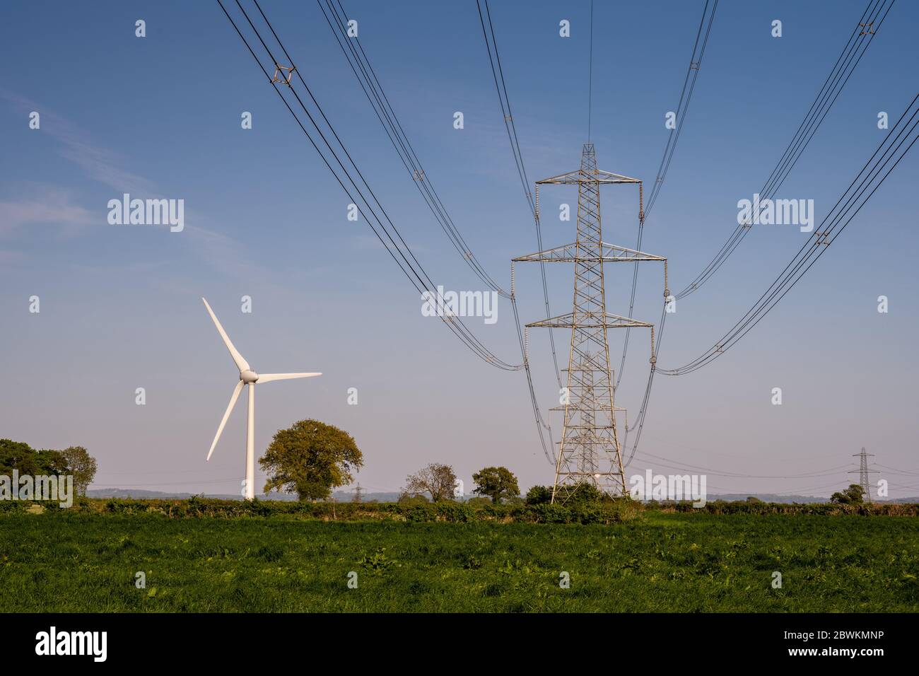 Wind turbines stand in farmland fields beside National Grid high ...