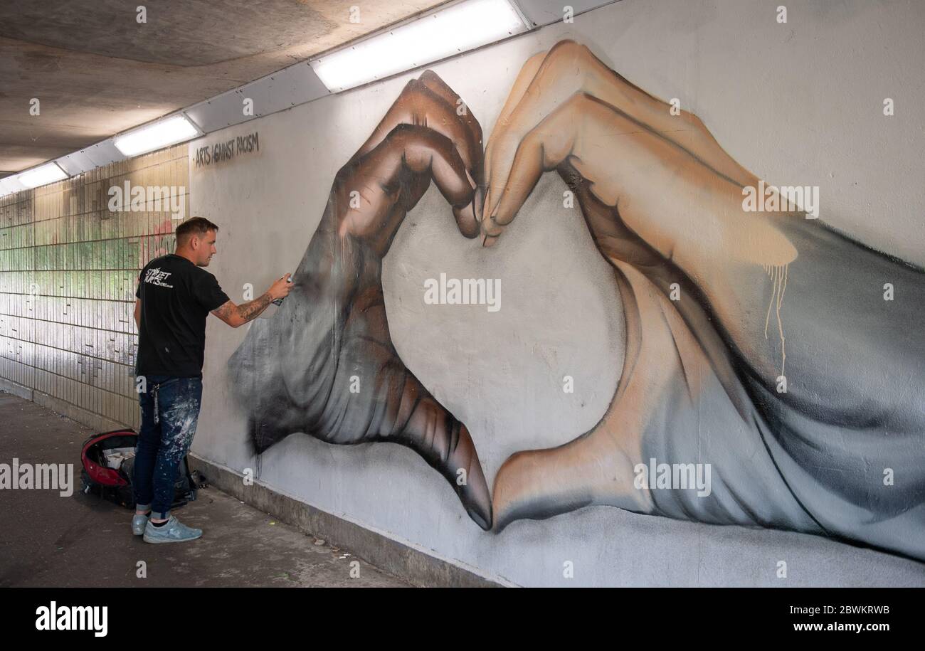 Street artist Nath Murdoch touches up his anti-racism mural in ...