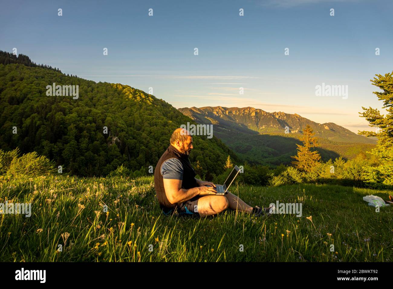 man working outdoors with laptop. Green spring mountain landscape Stock ...