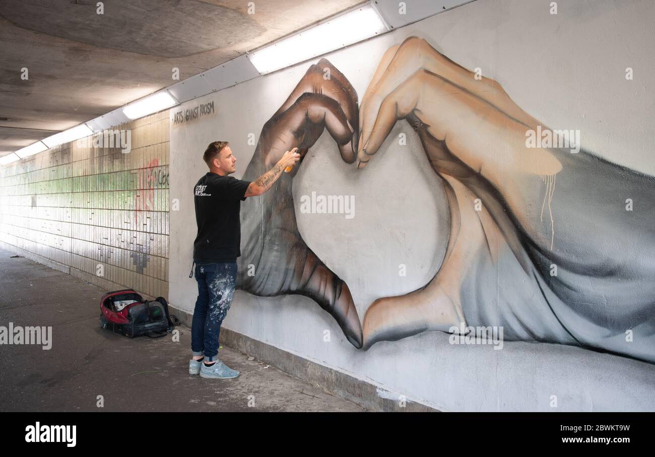 Street artist Nath Murdoch touches up his anti-racism mural in ...