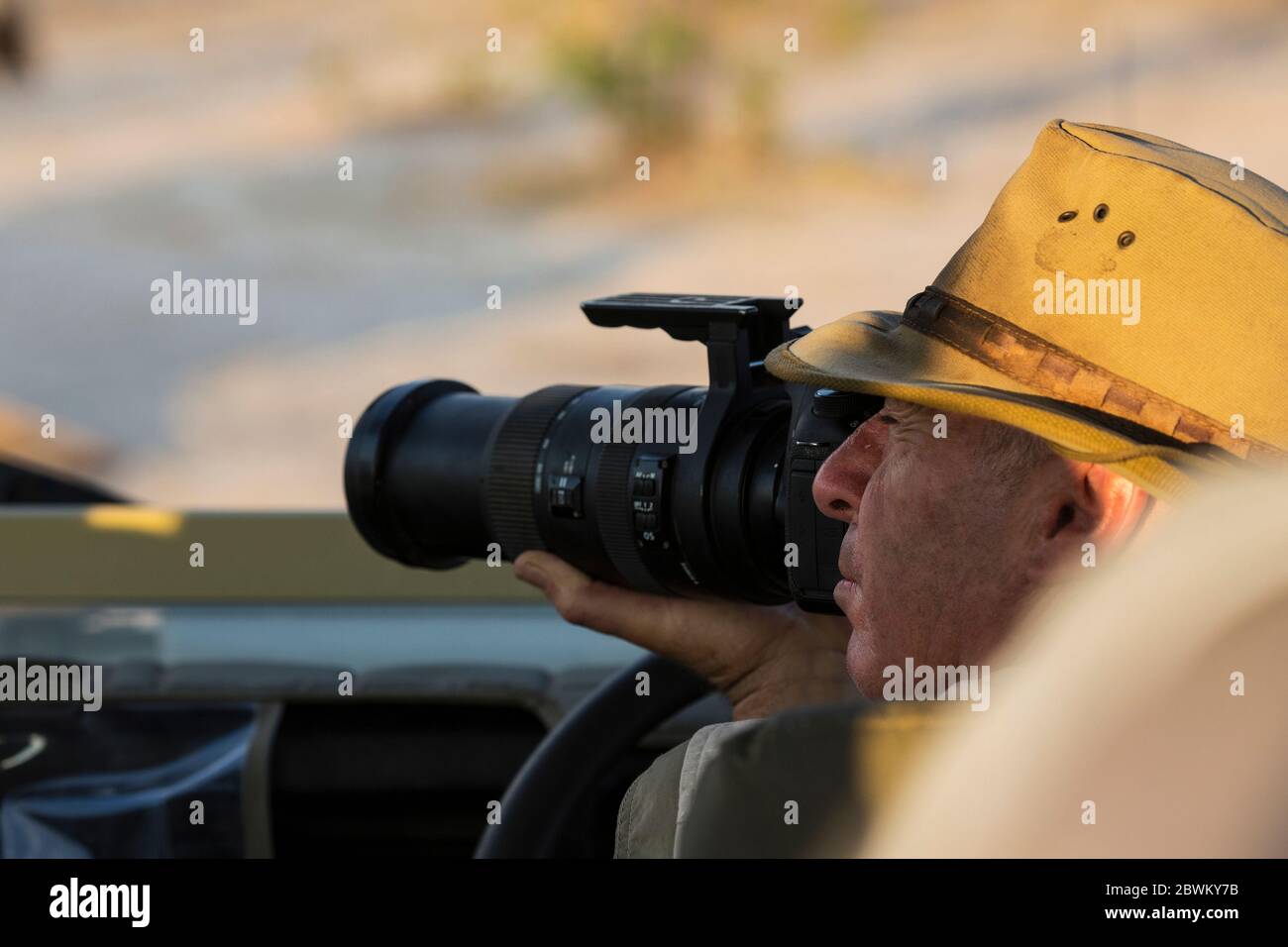 A man in a bush hat using a camera with a long lens Stock Photo - Alamy