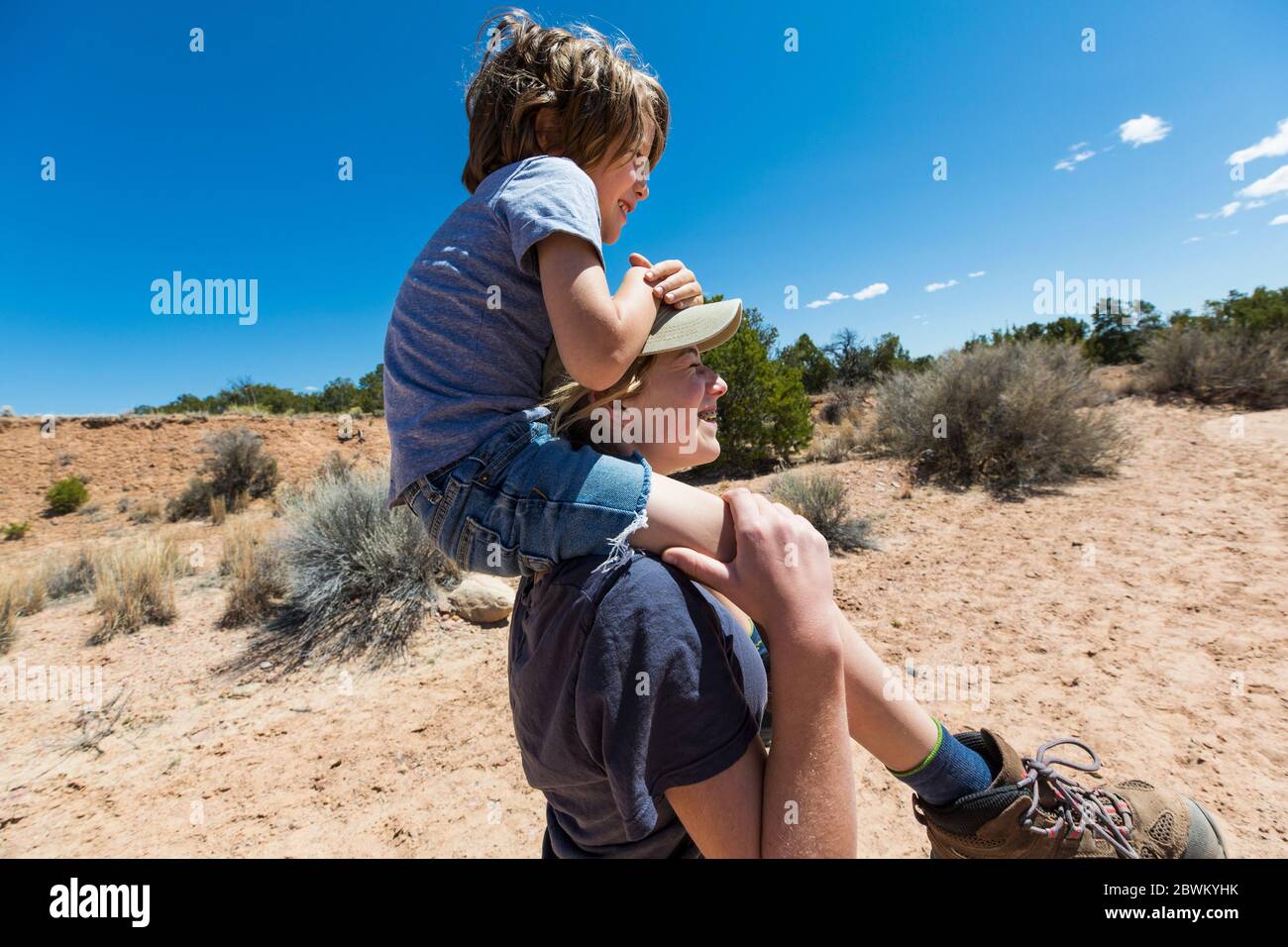 14 year old girl giving younger brother a piggyback ride, Galisteo ...