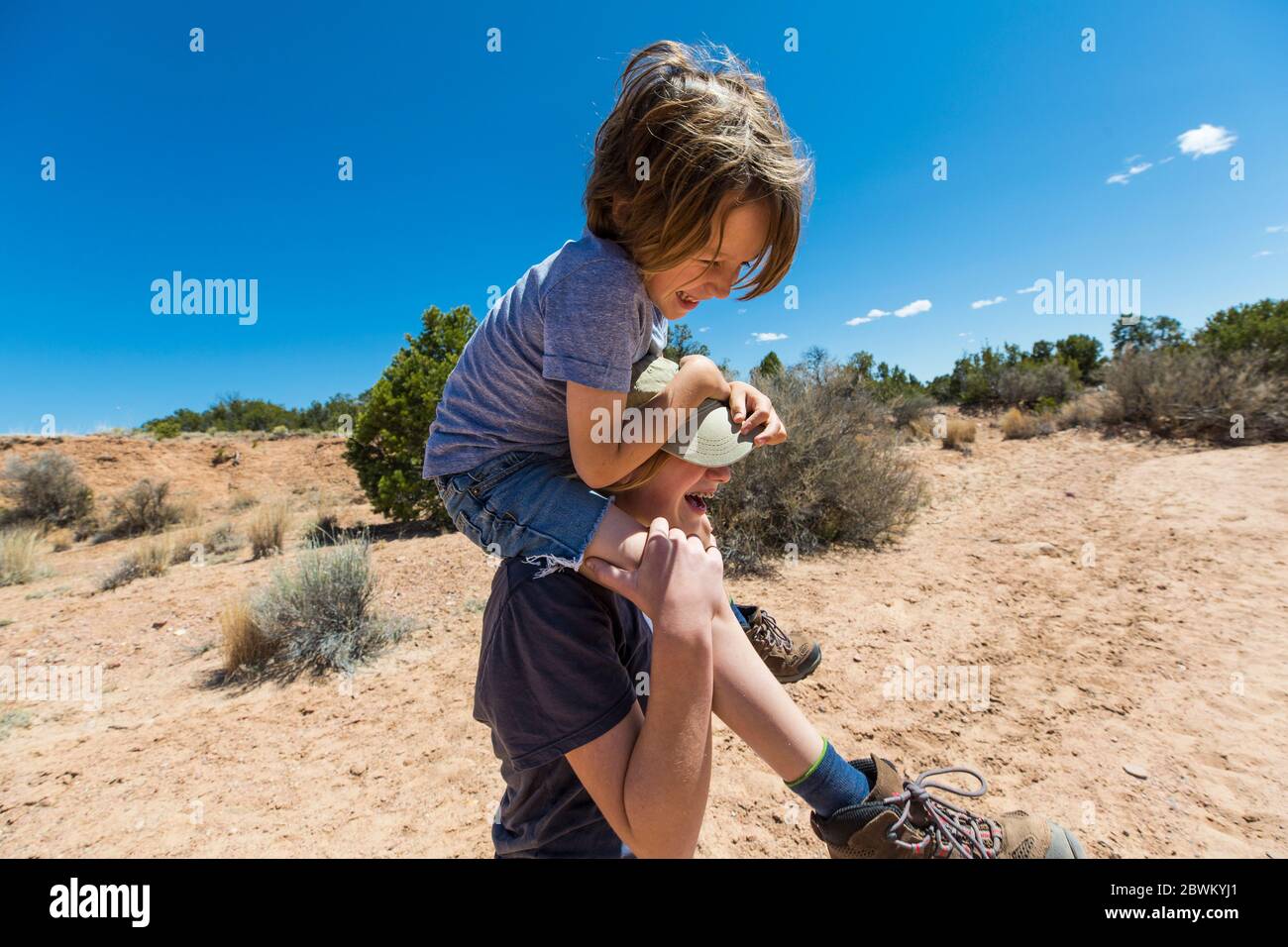 14 year old girl giving younger brother a piggyback ride, Galisteo ...