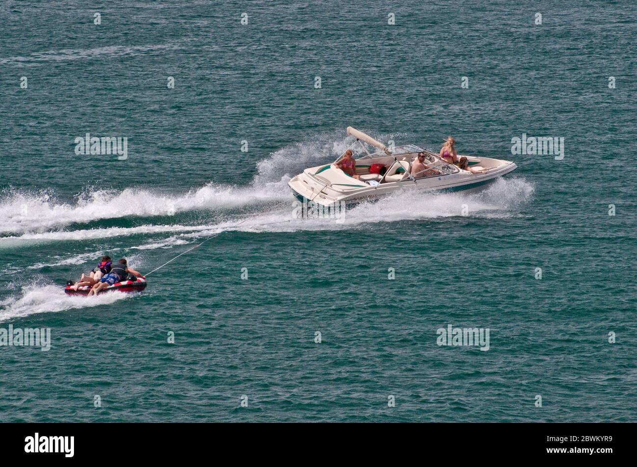 Speedboat towing riders in a rubber raft on Canyon Lake, artificial ...