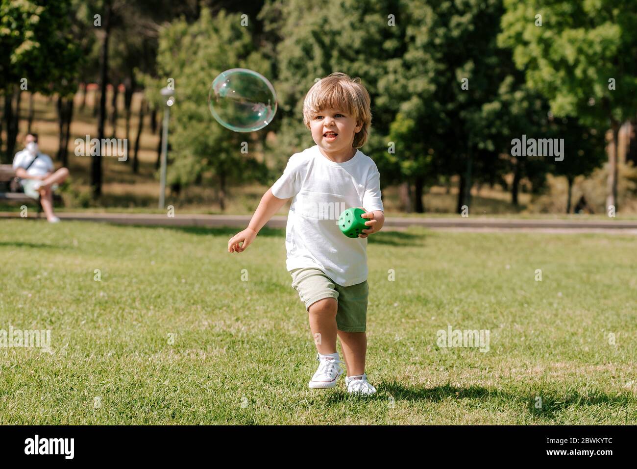Funny little boy catching soap bubbles in the summer on nature little ...