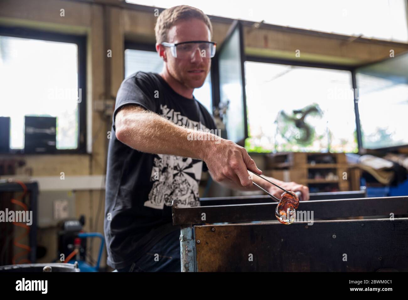 A student shaping glass at a workbench during a glassblowing lesson at ...