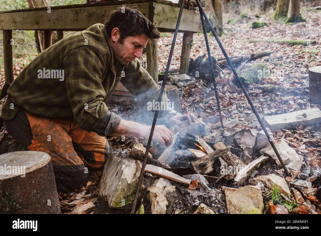 Man starting a camp fire in a forest Stock Photo - Alamy