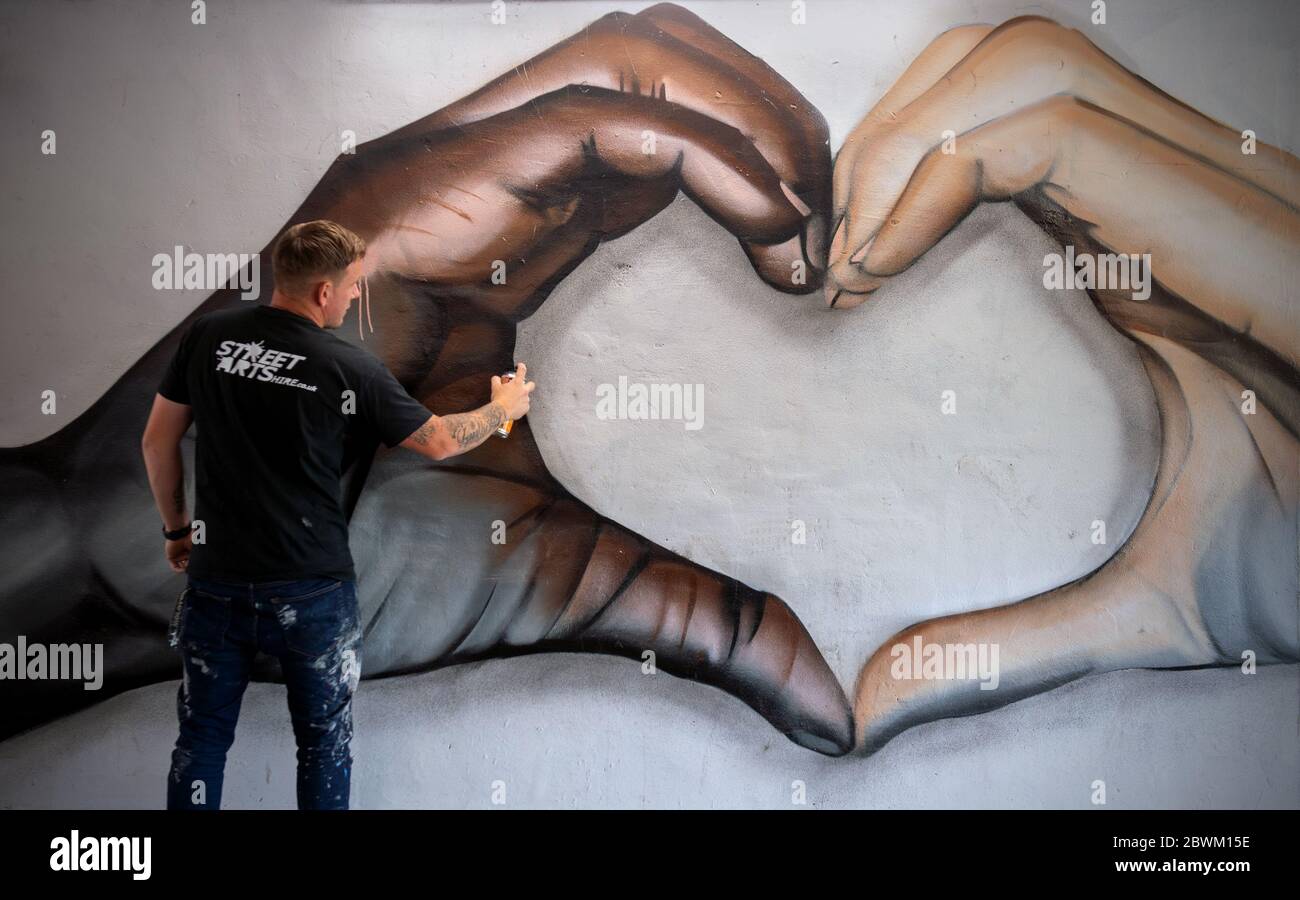 Street artist Nath Murdoch touches up his anti-racism mural in ...