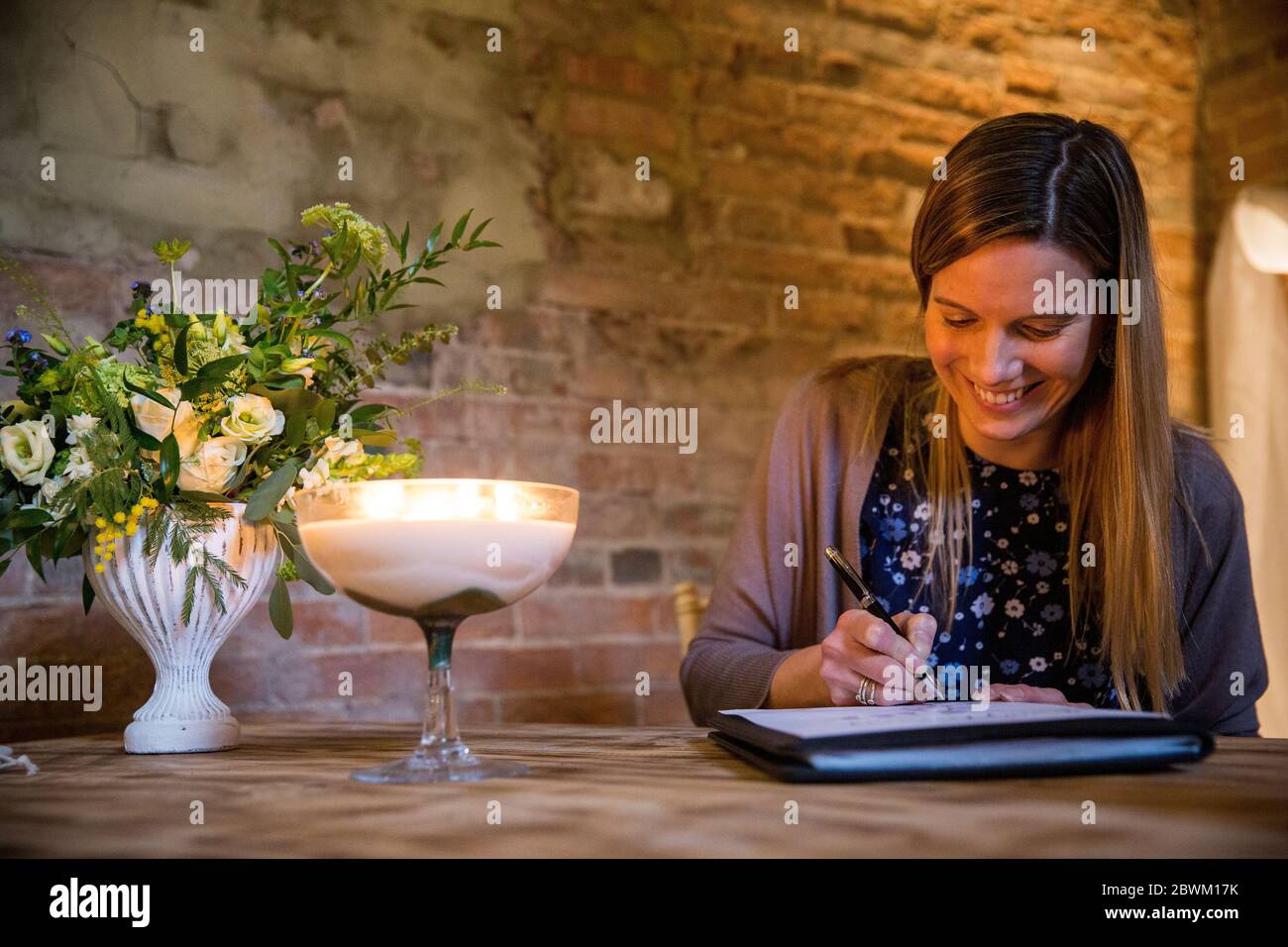 Witness signing certificate during naming ceremony in an historic barn ...