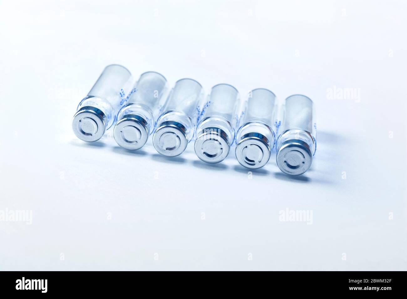 Row of medical glass vial with solution for injection on white ...