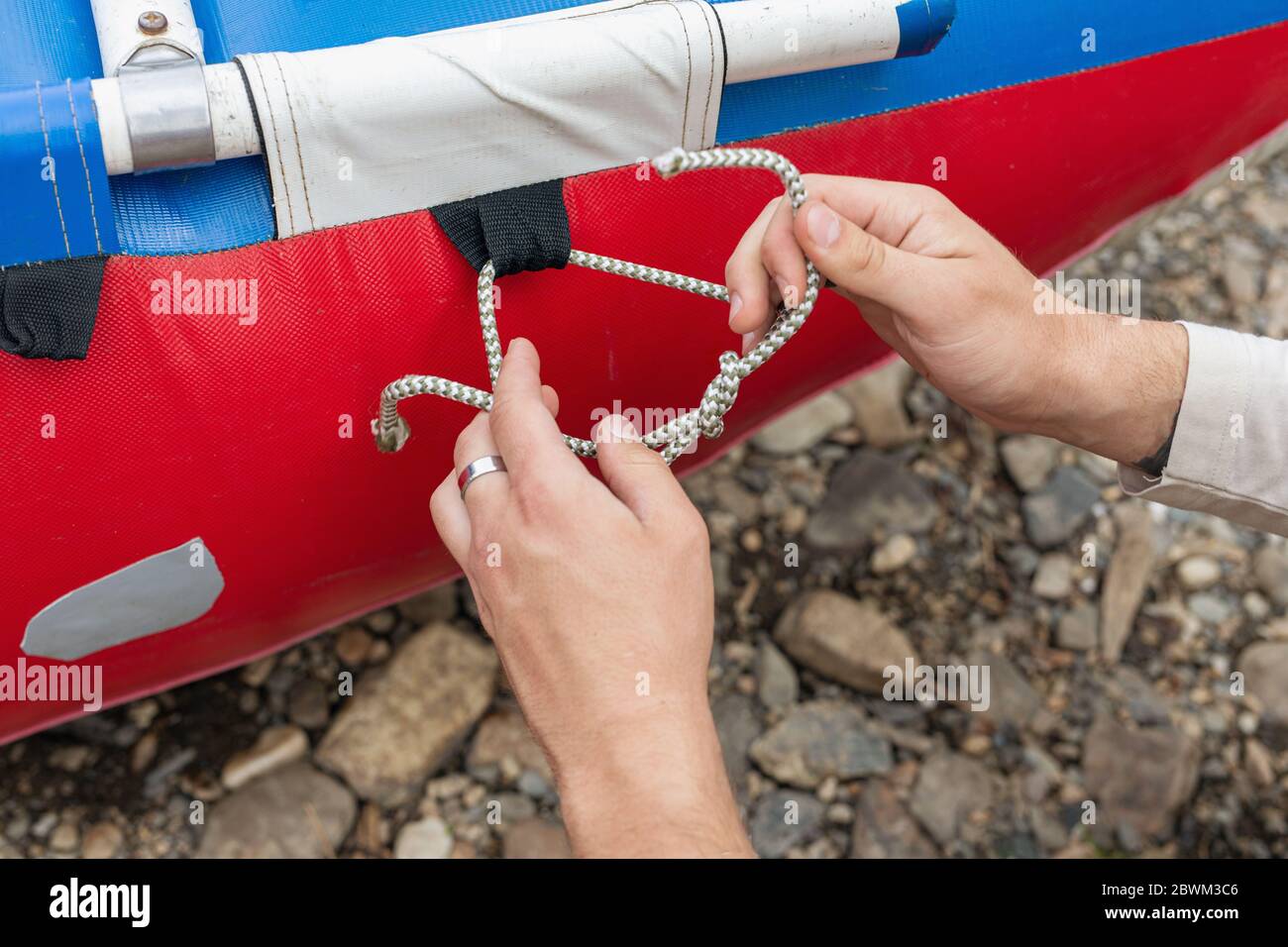 man holds knot in his hands and ties a rope aboard a boat, ship or ...