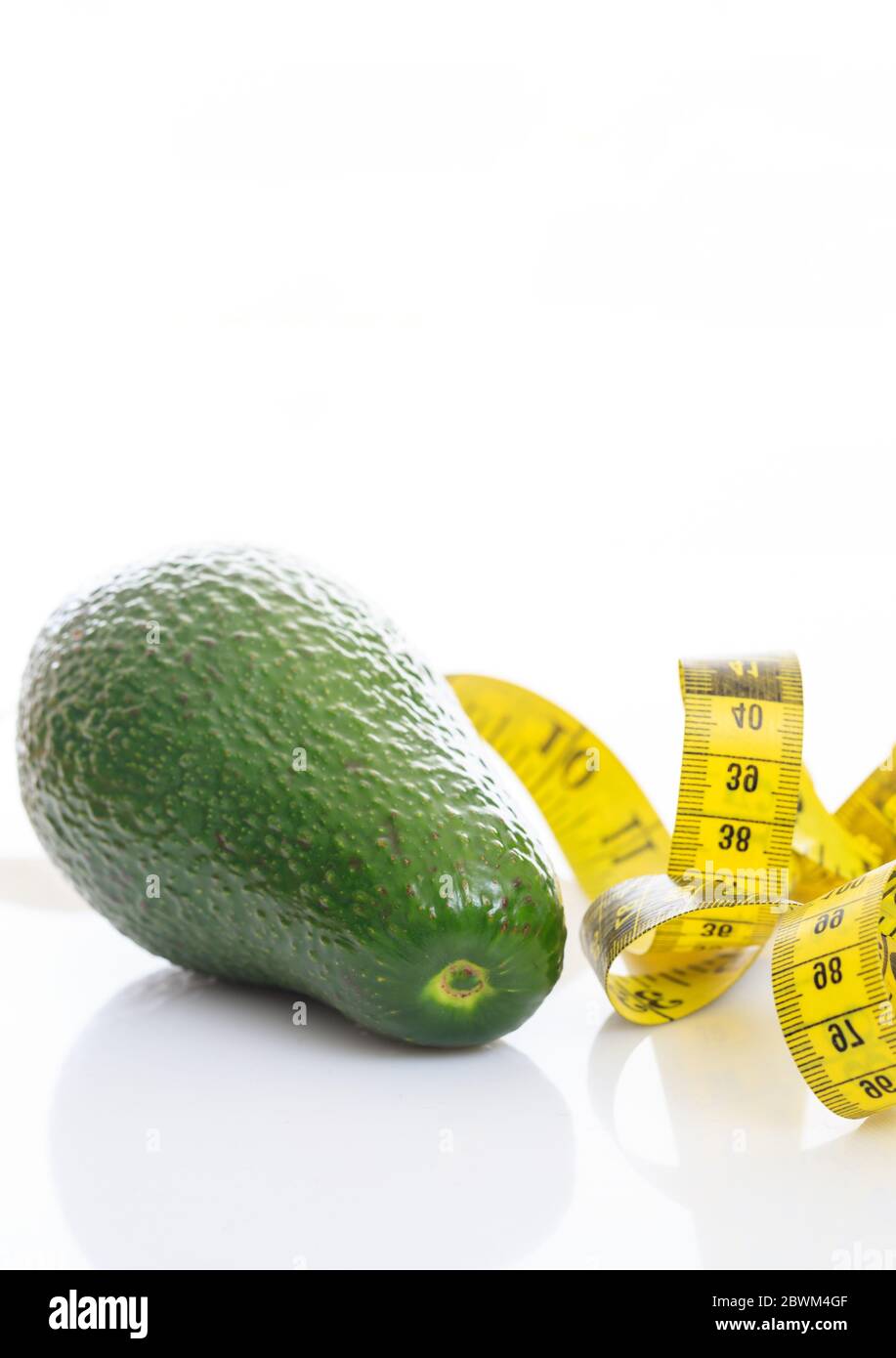 Healthy lifestyle concept. Avocado and measure tape on white background ...