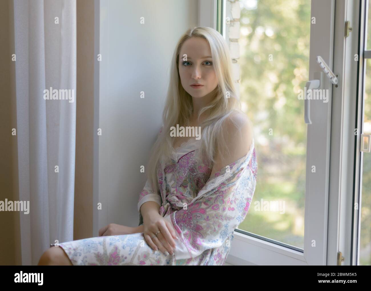 Beautiful young woman sitting by the window. Selective focus Stock ...
