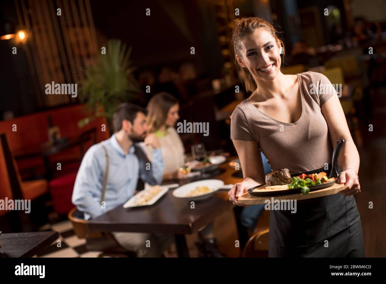 Pretty waiter woman serving group of friends with food in the restaura ...
