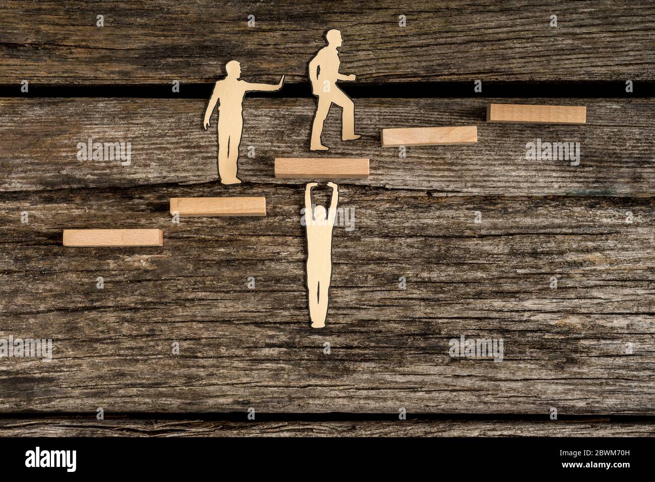 Teamwork concept using cut outs of paper men with one supporting steps ...