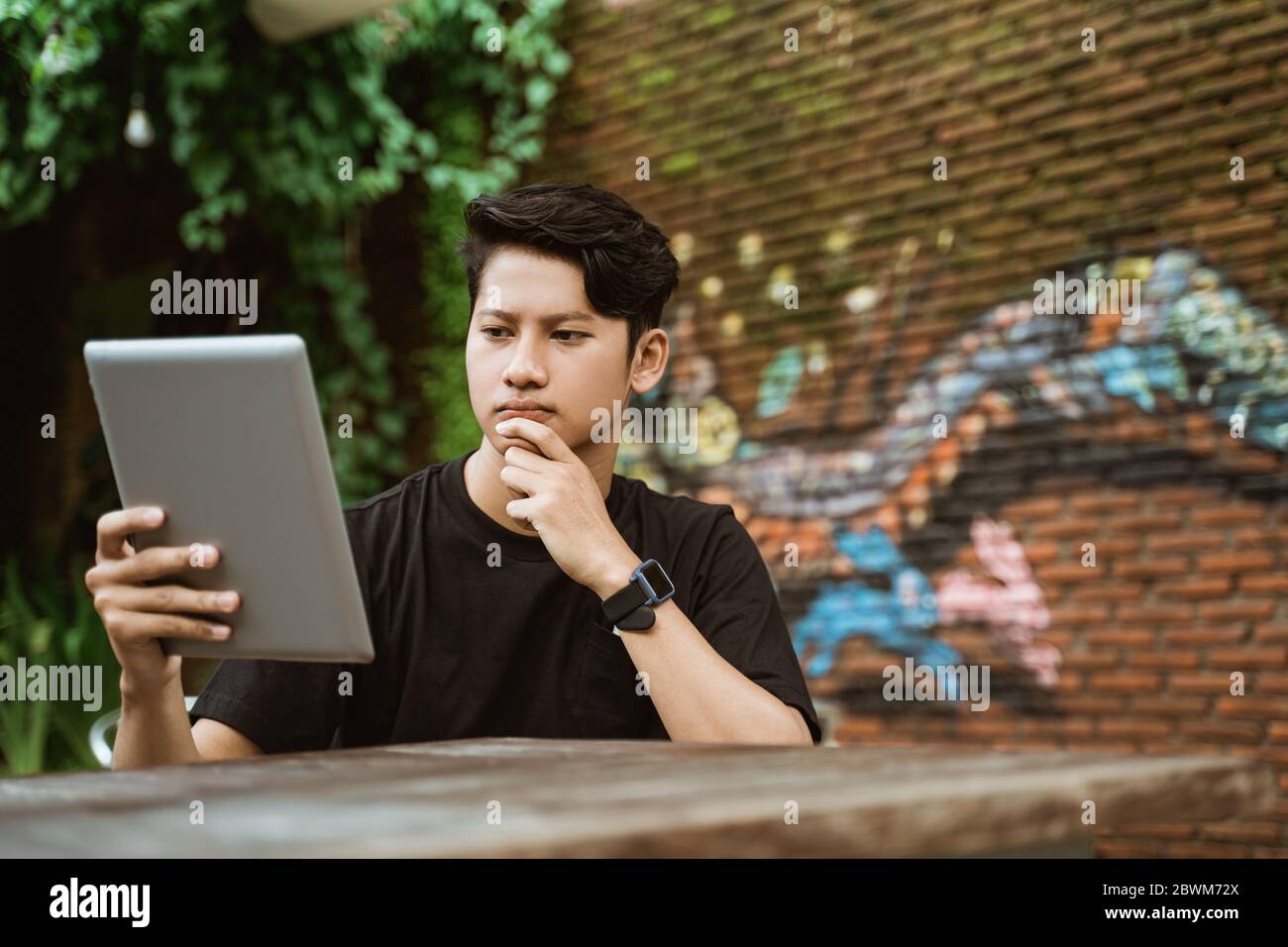 Serious young man using a tablet pc for work outdoor Stock Photo - Alamy