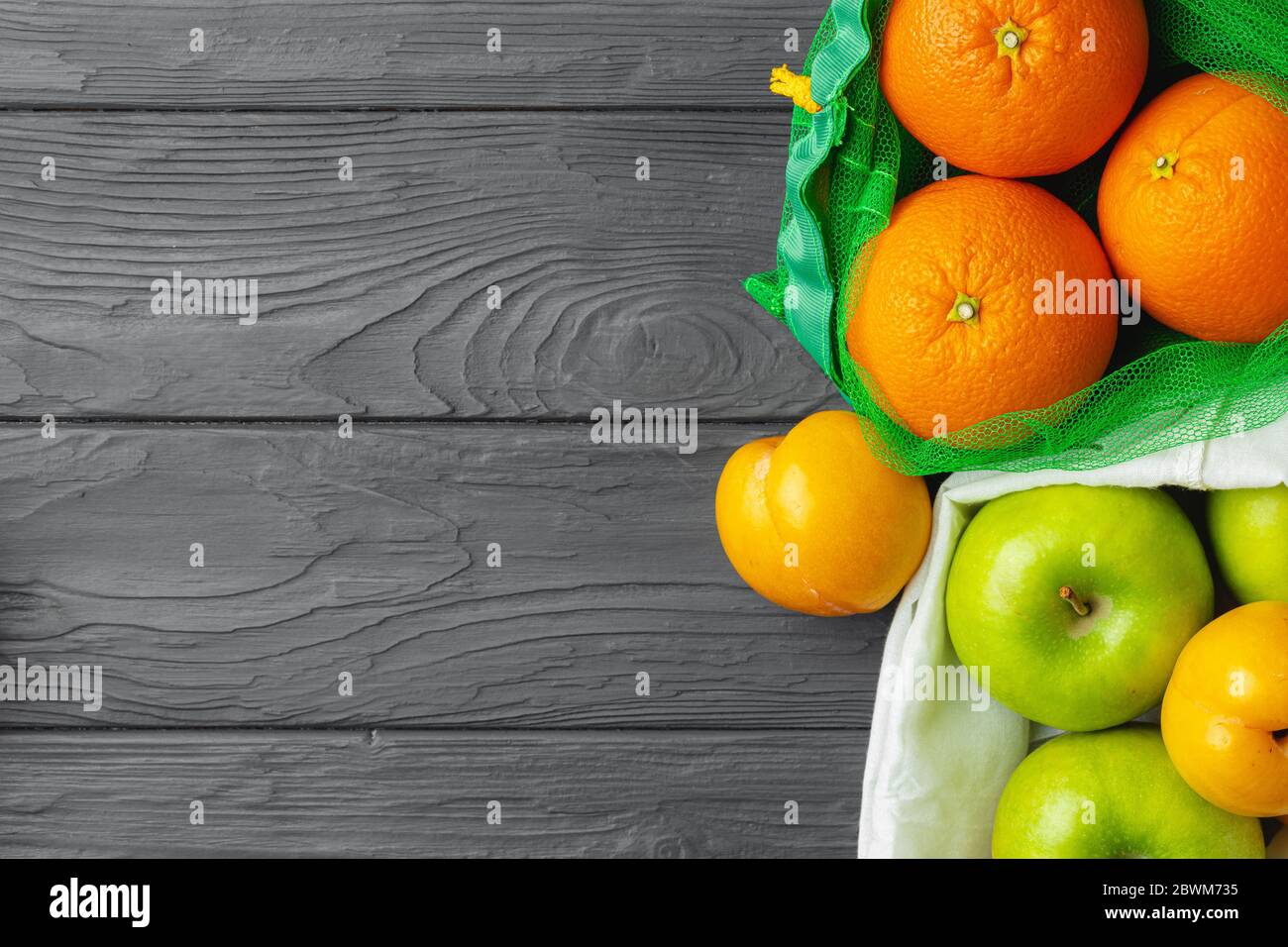 Apples and oranges in packets on black wooden table Stock Photo - Alamy