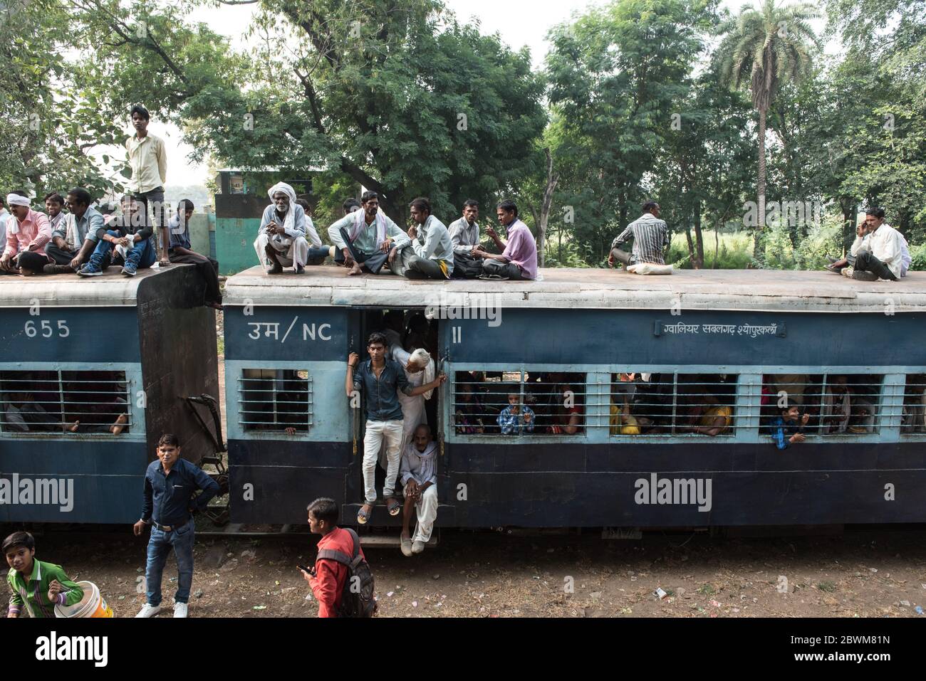 Passengers on top of overcrowded train at a train station in rural ...