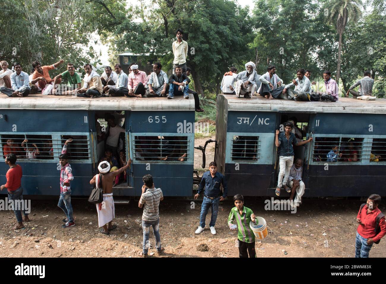 Passengers on top of overcrowded train at a train station in rural ...