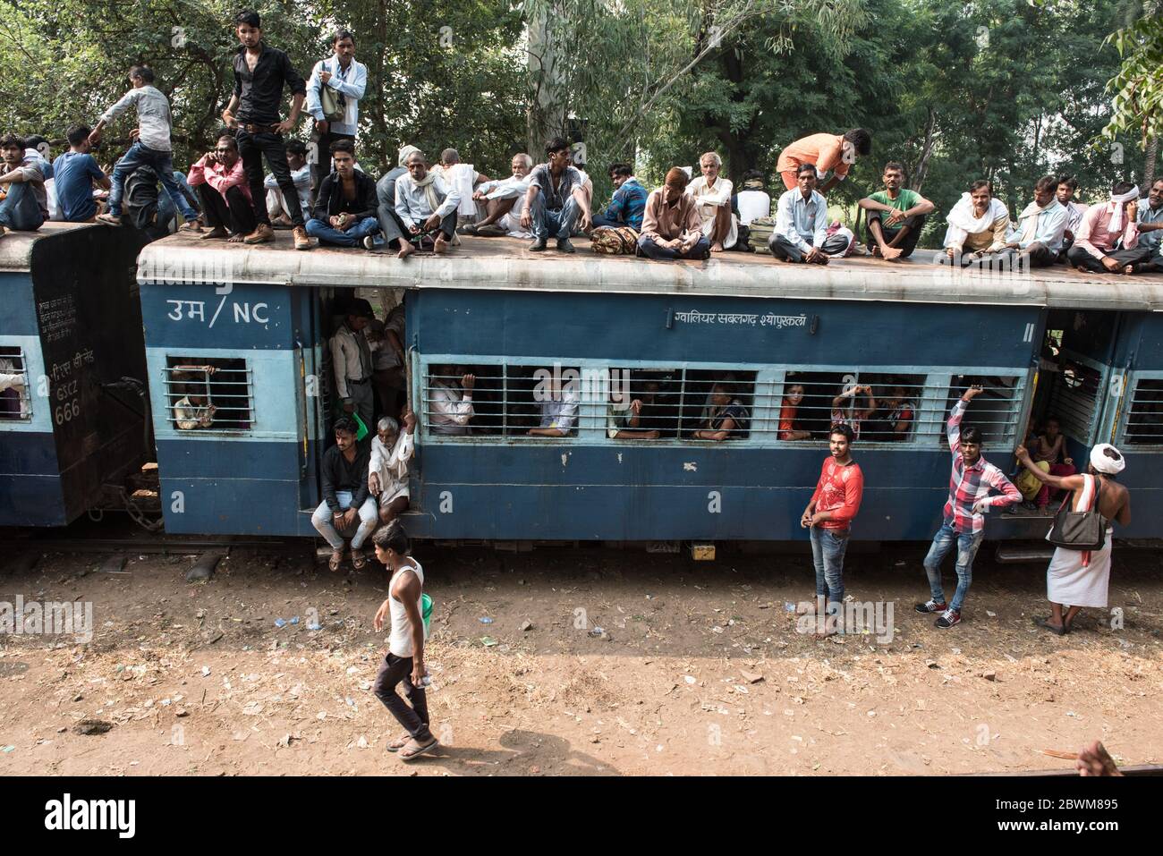 Passengers on top of overcrowded train at a train station in rural ...