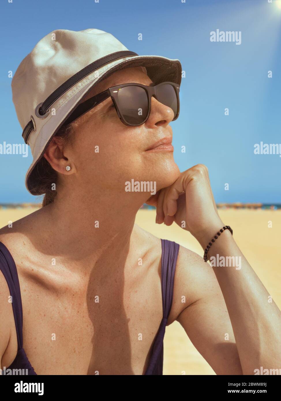 Portrait Of A Mature Woman Wearing Hat And Sunglasses Looking Away At A