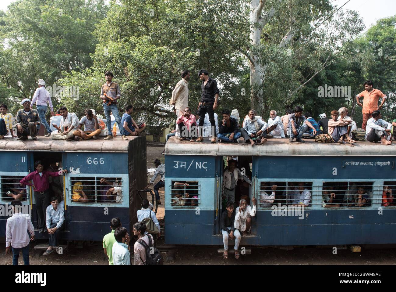 Passengers on top of overcrowded train at a train station in rural ...