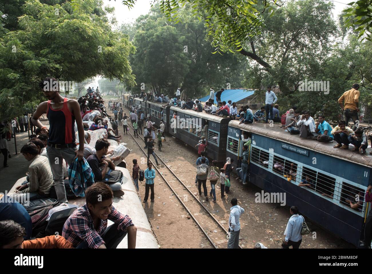 Passengers on top of overcrowded train at a train station in rural ...