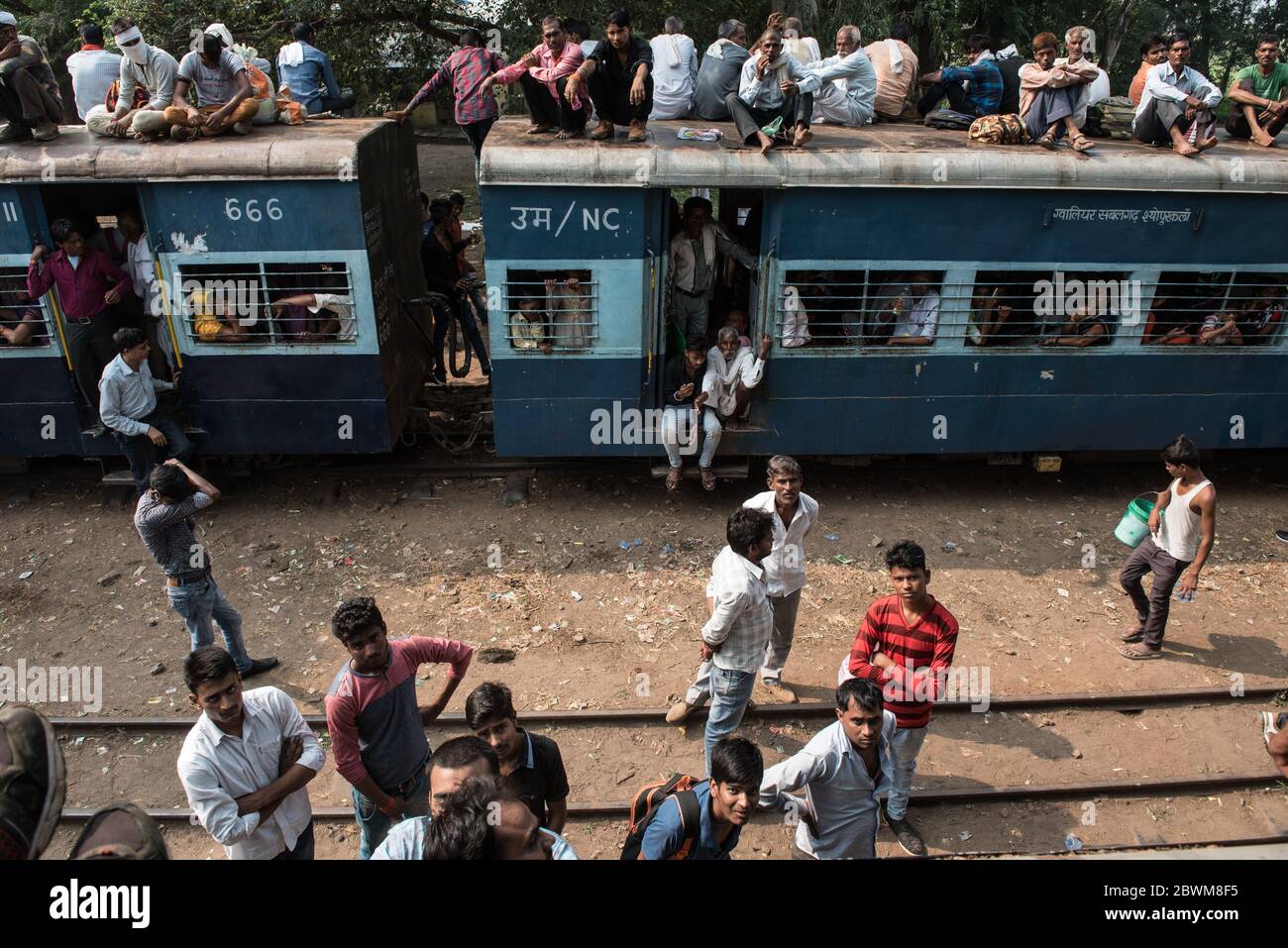 Passengers on top of overcrowded train at a train station in rural ...