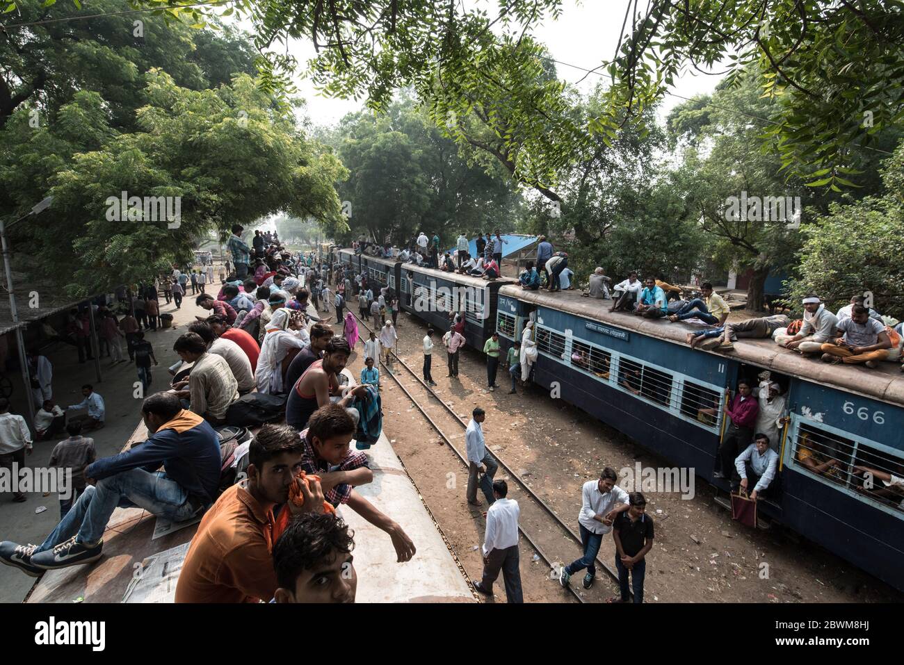 Passengers on top of overcrowded train at a train station in rural ...