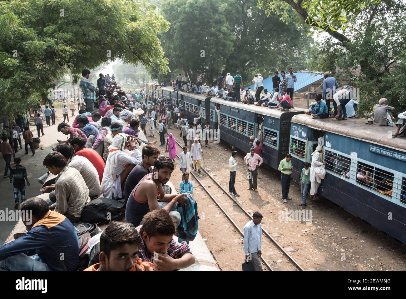 Passengers on top of overcrowded train at a train station in rural ...