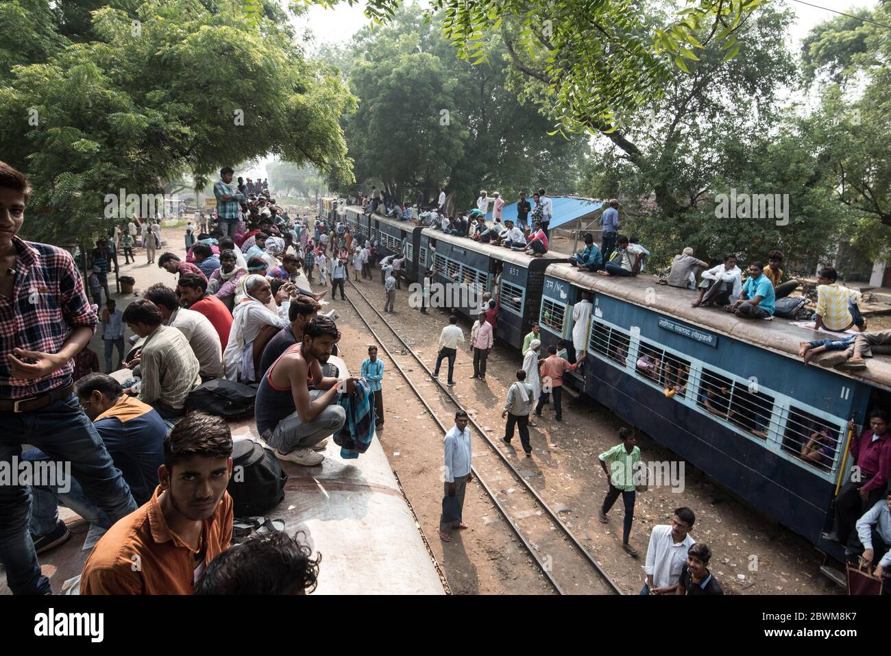 Passengers on top of overcrowded train at a train station in rural ...