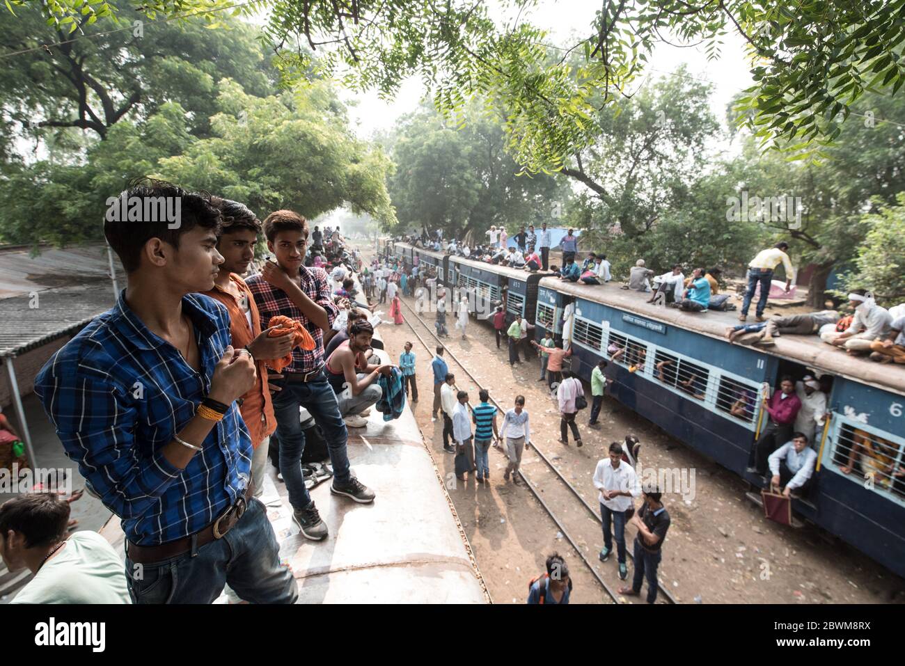 Passengers on top of overcrowded train at a train station in rural ...