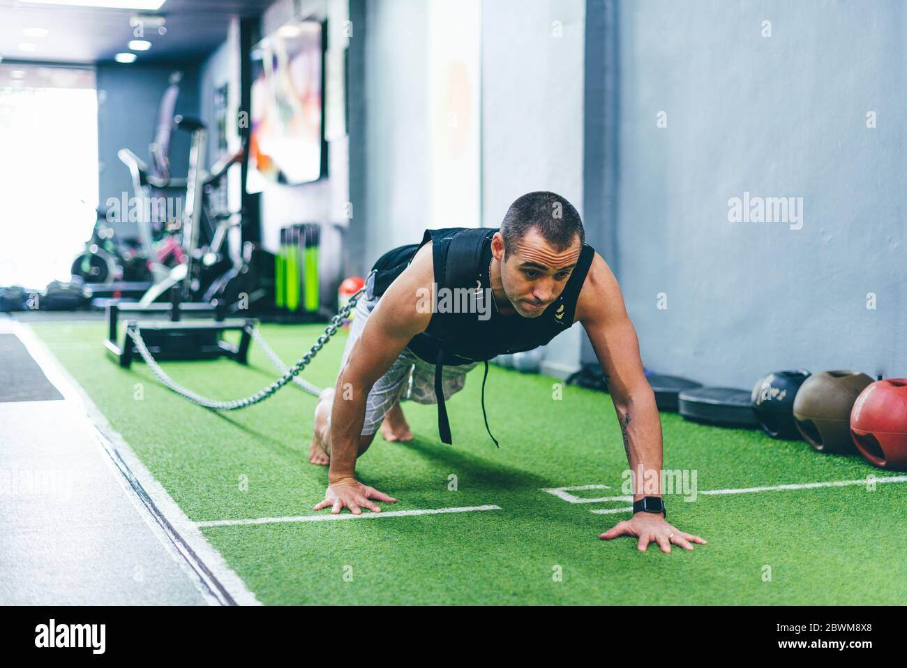 Latin boy doing physical exercise in gym dragging a sled with weight ...