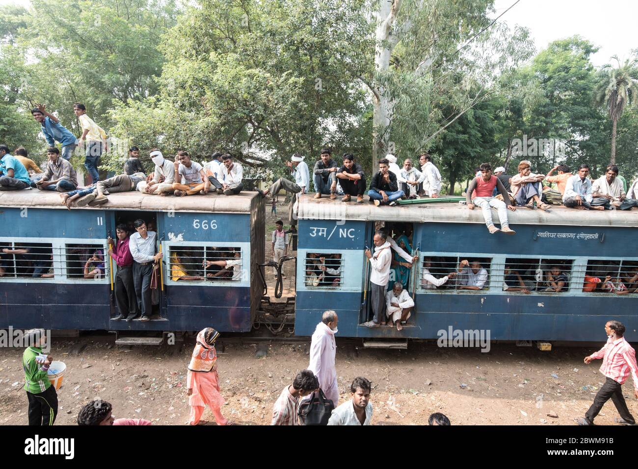 Passengers on top of overcrowded train at a train station in rural ...