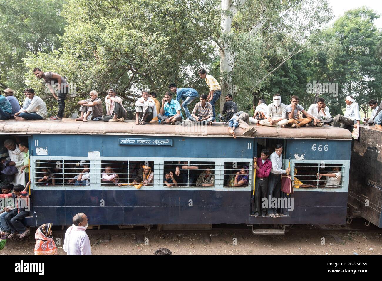 Passengers on top of overcrowded train at a train station in rural ...