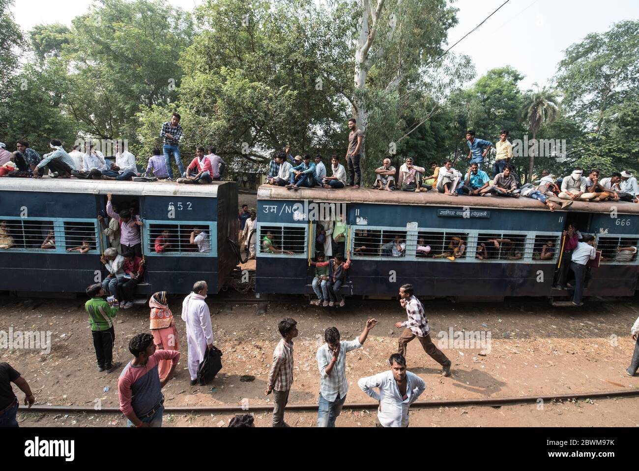 Passengers on top of overcrowded train at a train station in rural ...