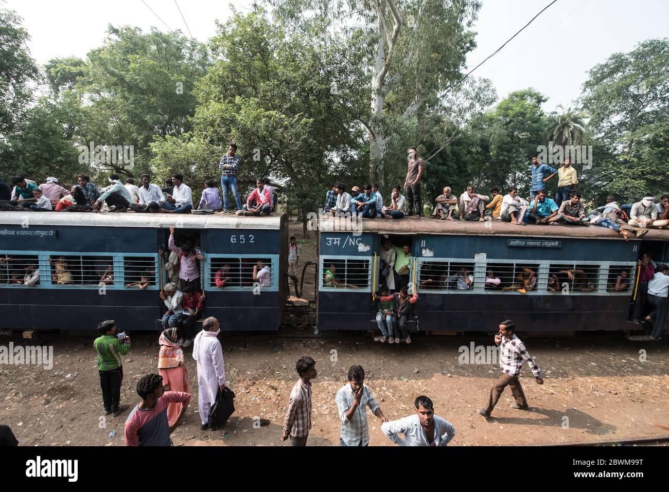 Passengers on top of overcrowded train at a train station in rural ...
