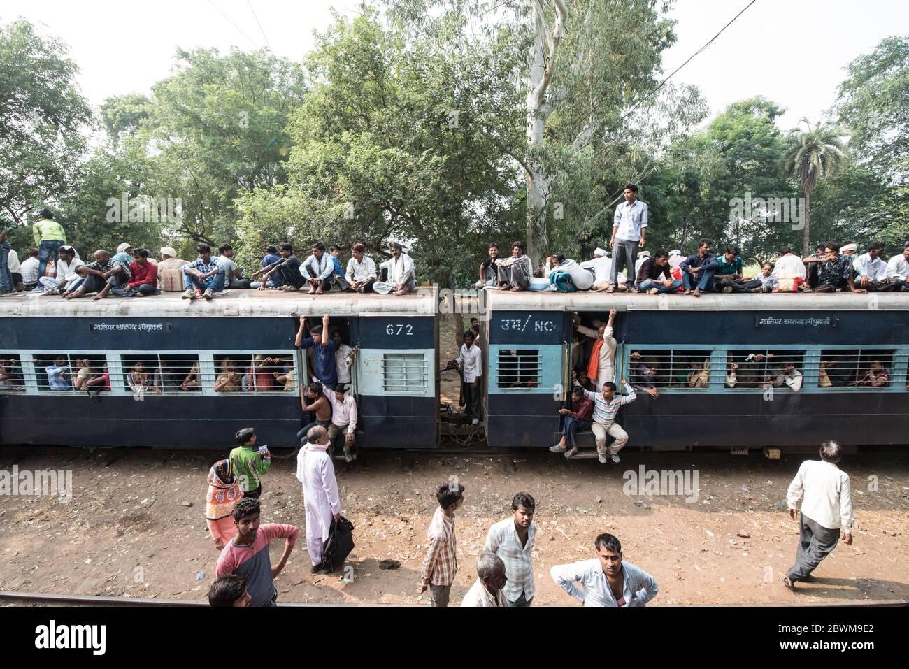 Passengers on top of overcrowded train at a train station in rural ...