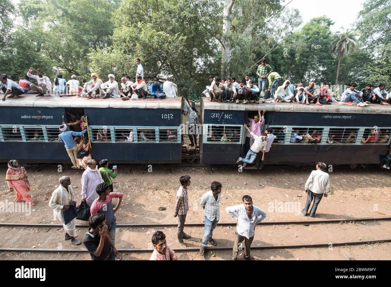 Passengers on top of overcrowded train at a train station in rural ...