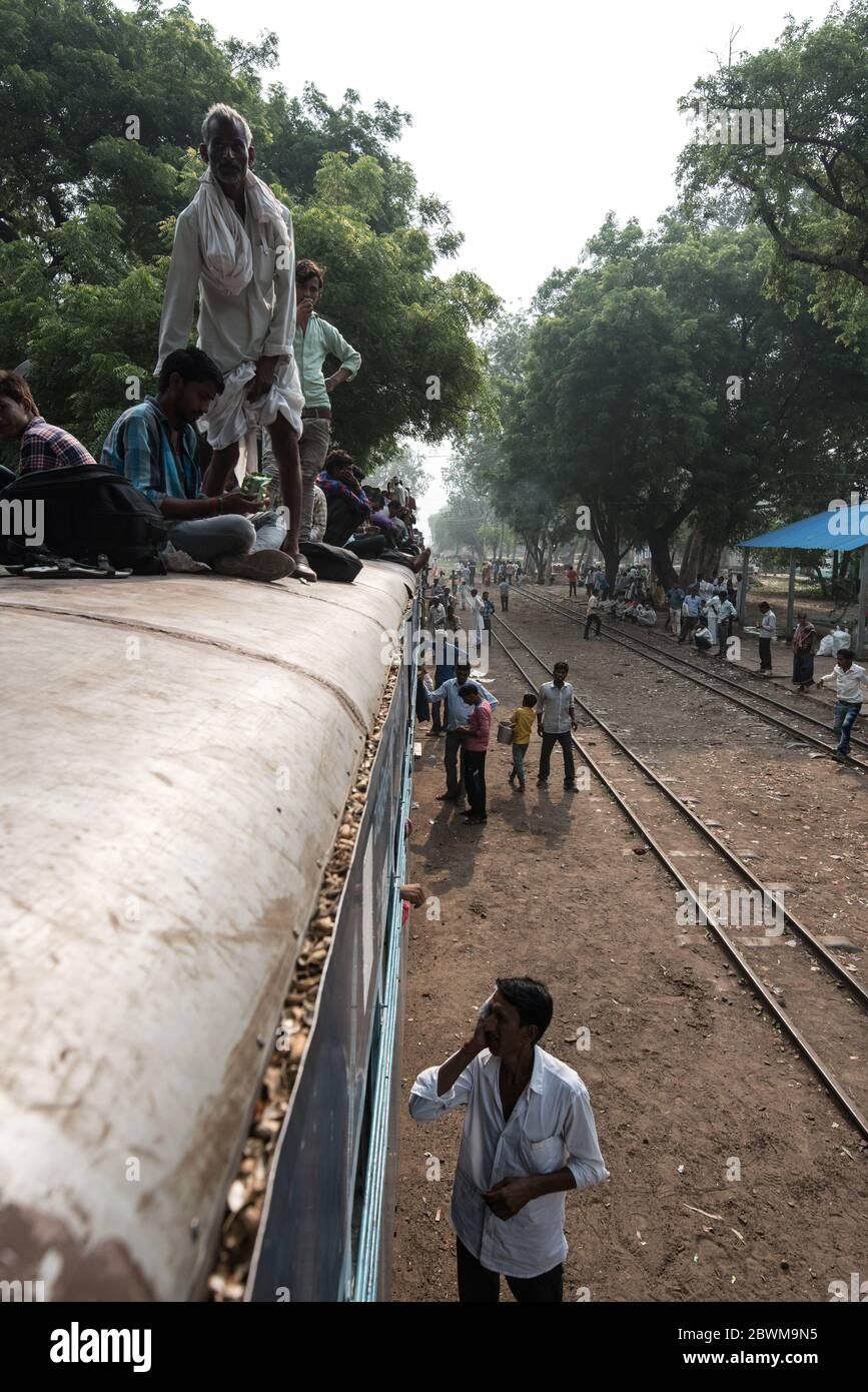 Men on top of overcrowded train passes through a small town in Madhya ...