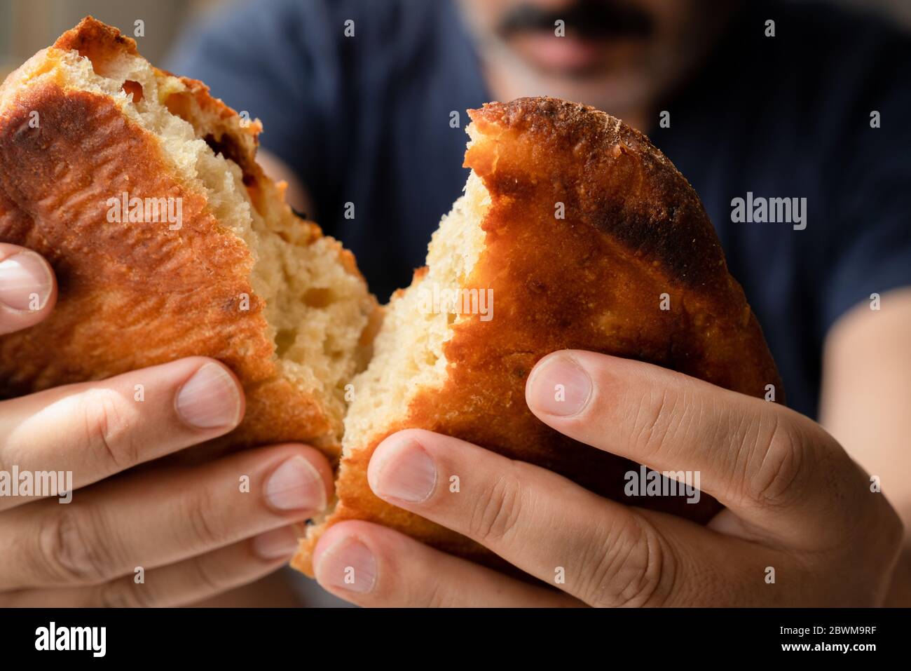 Freshly baked bread from the baker. Baker holding fresh bread in the ...