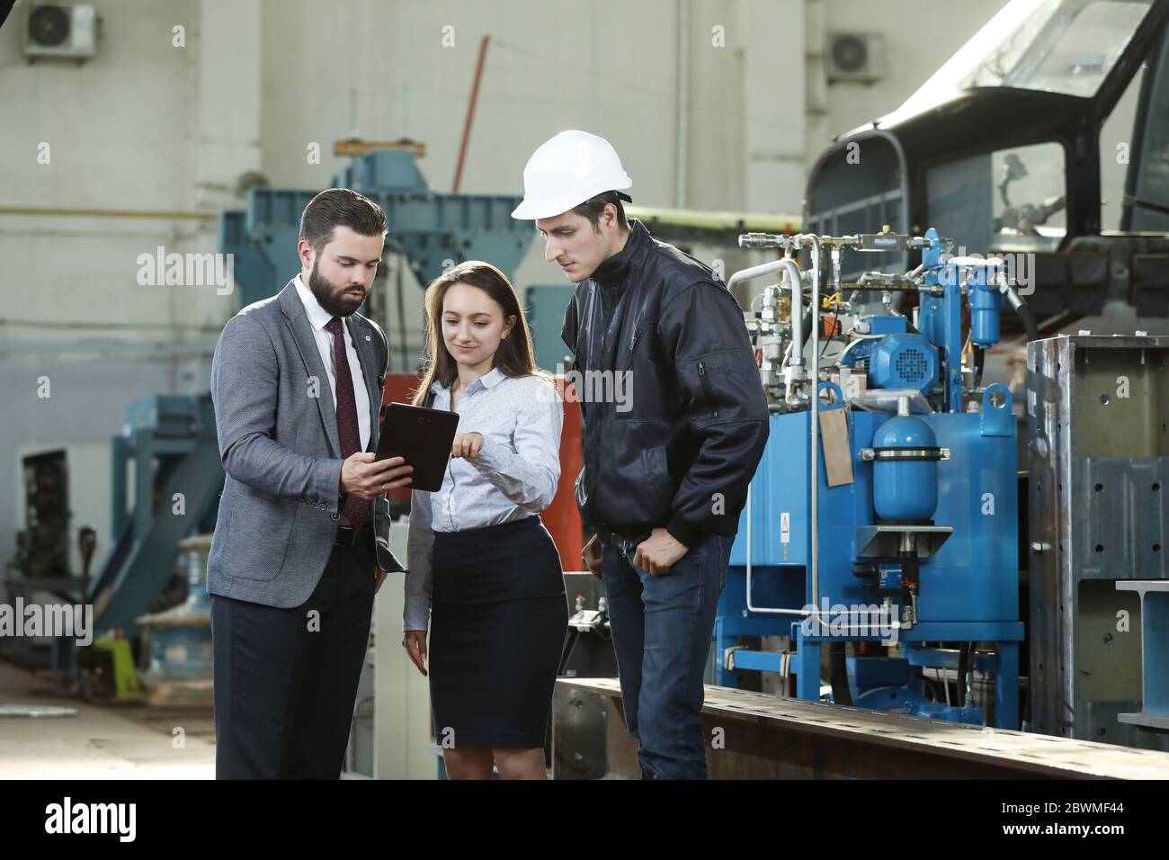 Portrait of a solid businessman with his secretary and factory engineer ...