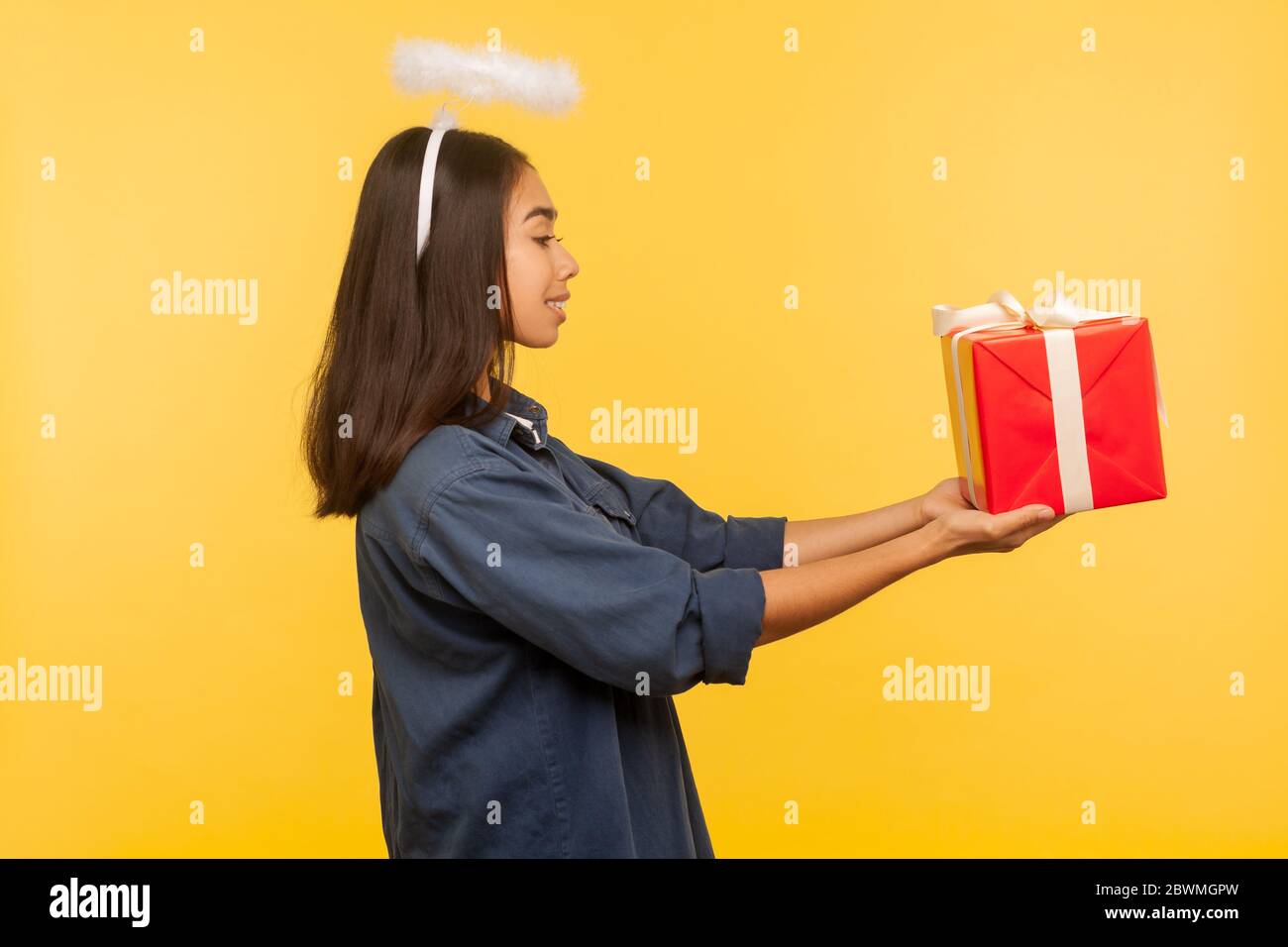 Take this holiday present! Side view of kind generous angelic girl with ...