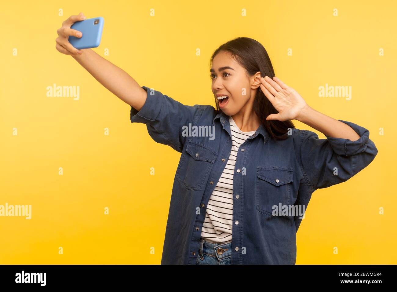 Portrait of friendly stylish girl in denim shirt taking selfie or ...